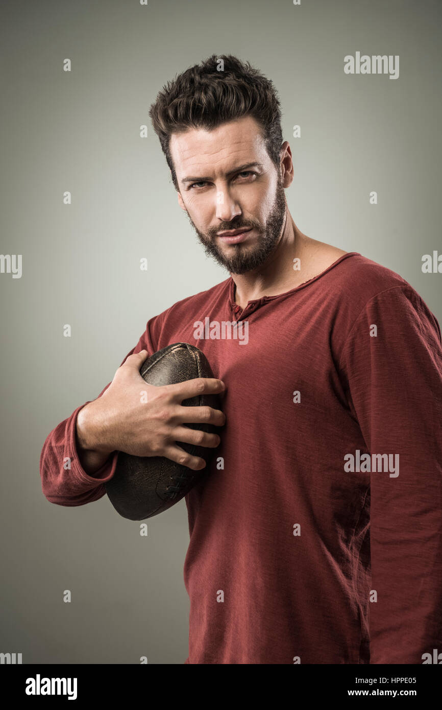 Young attractive football player playing with ball on gray background ...
