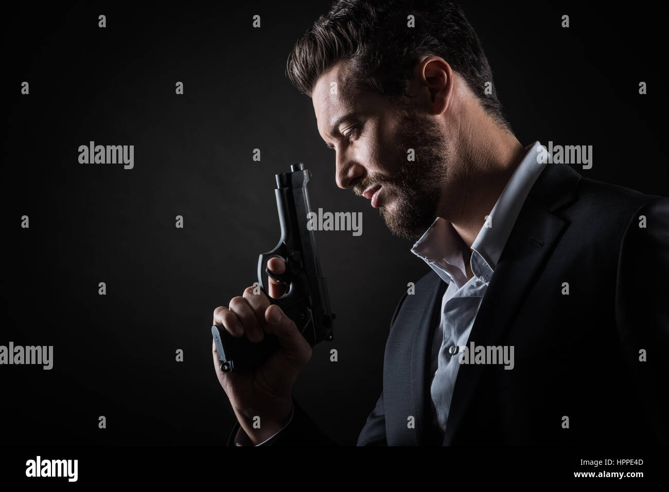 Brave cool man holding a gun on dark background Stock Photo - Alamy