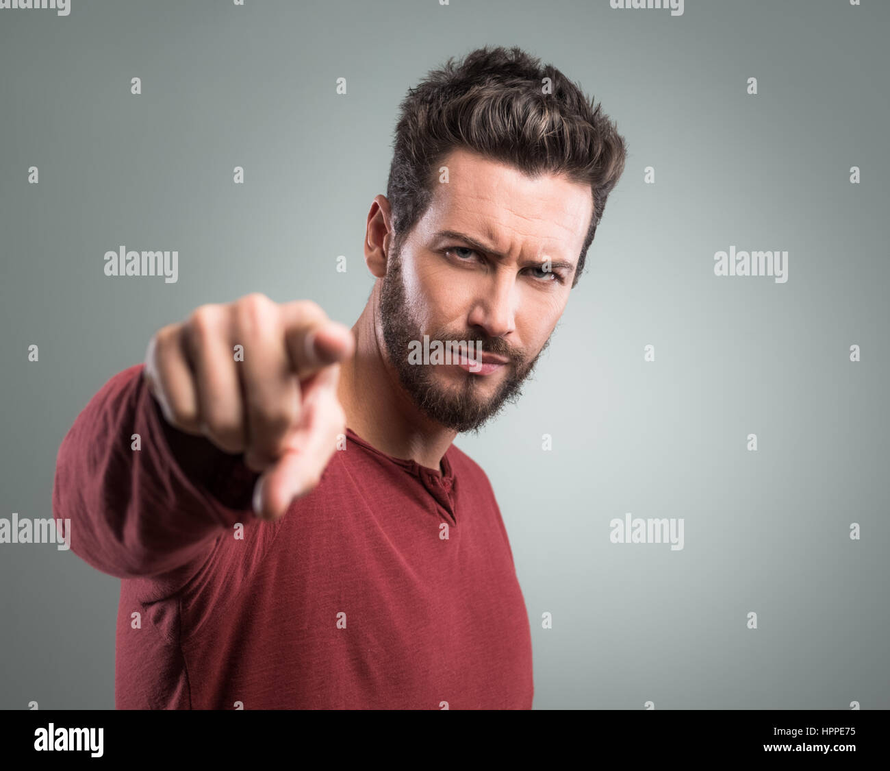 Angry attractive young man pointing at camera on gray background Stock ...