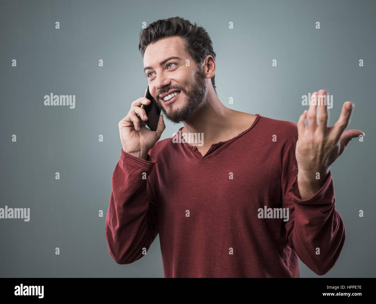Young smiling man having a phone call and gesturing Stock Photo - Alamy