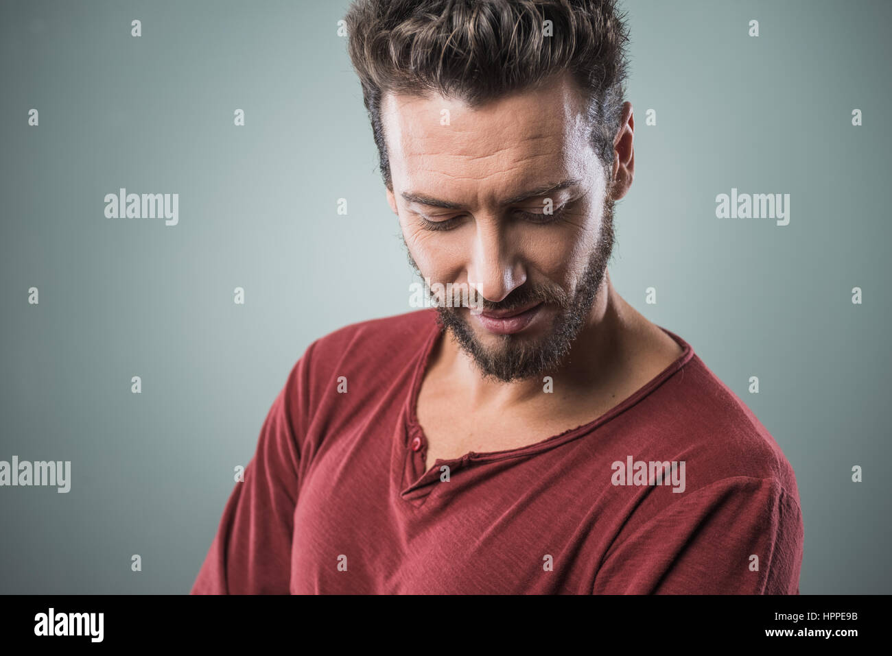Cool expressive young man looking down on gray background Stock Photo ...