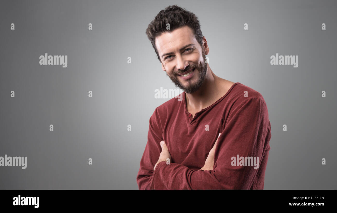 Confident attractive man smiling and posing on gray background Stock ...