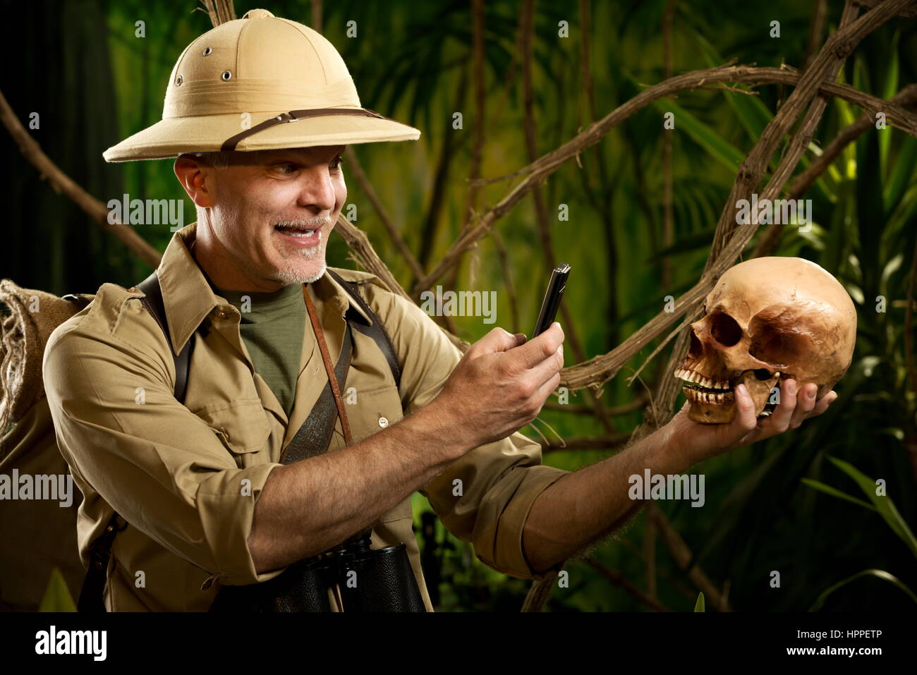 Smiling explorer taking a picture of a skull in the jungle with a ...