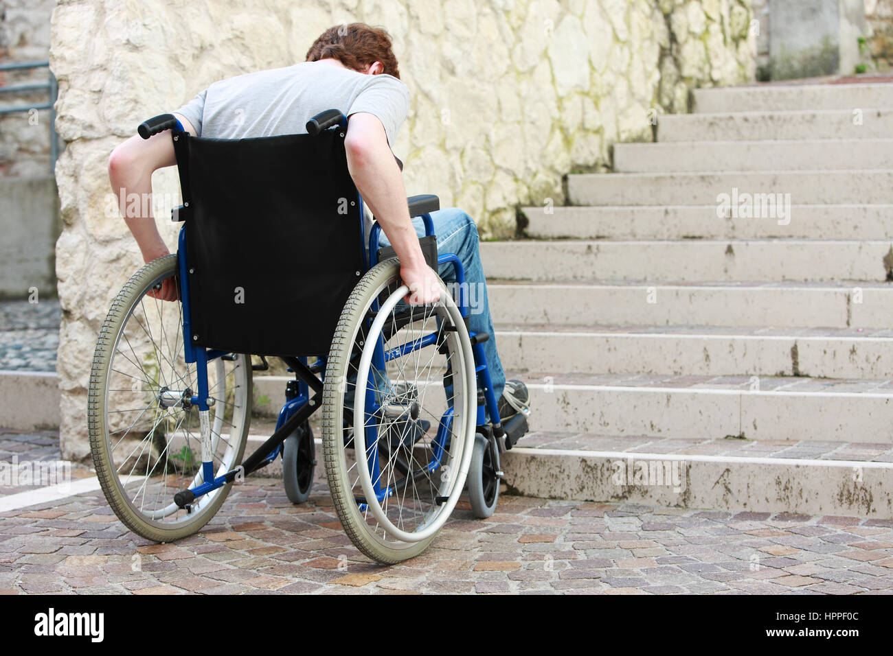 A young man in a wheelchair who can't get up the stairs Stock Photo - Alamy