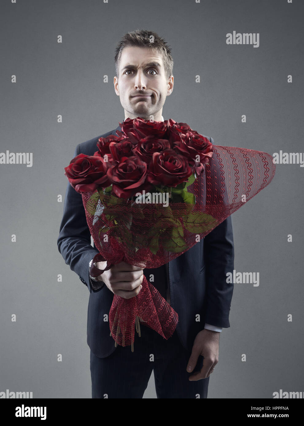 Shocked man holding out large bouquet of red roses Stock Photo - Alamy