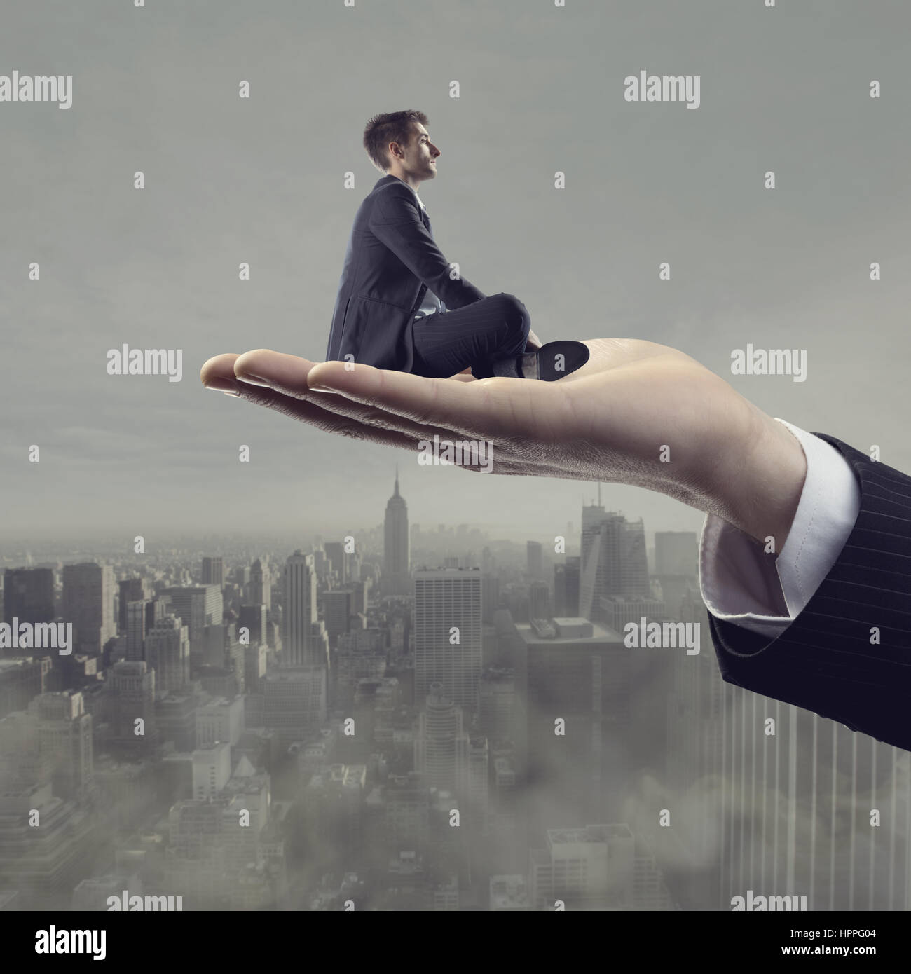 Businessman sitting on hand palm and looking away with cityscape and ...