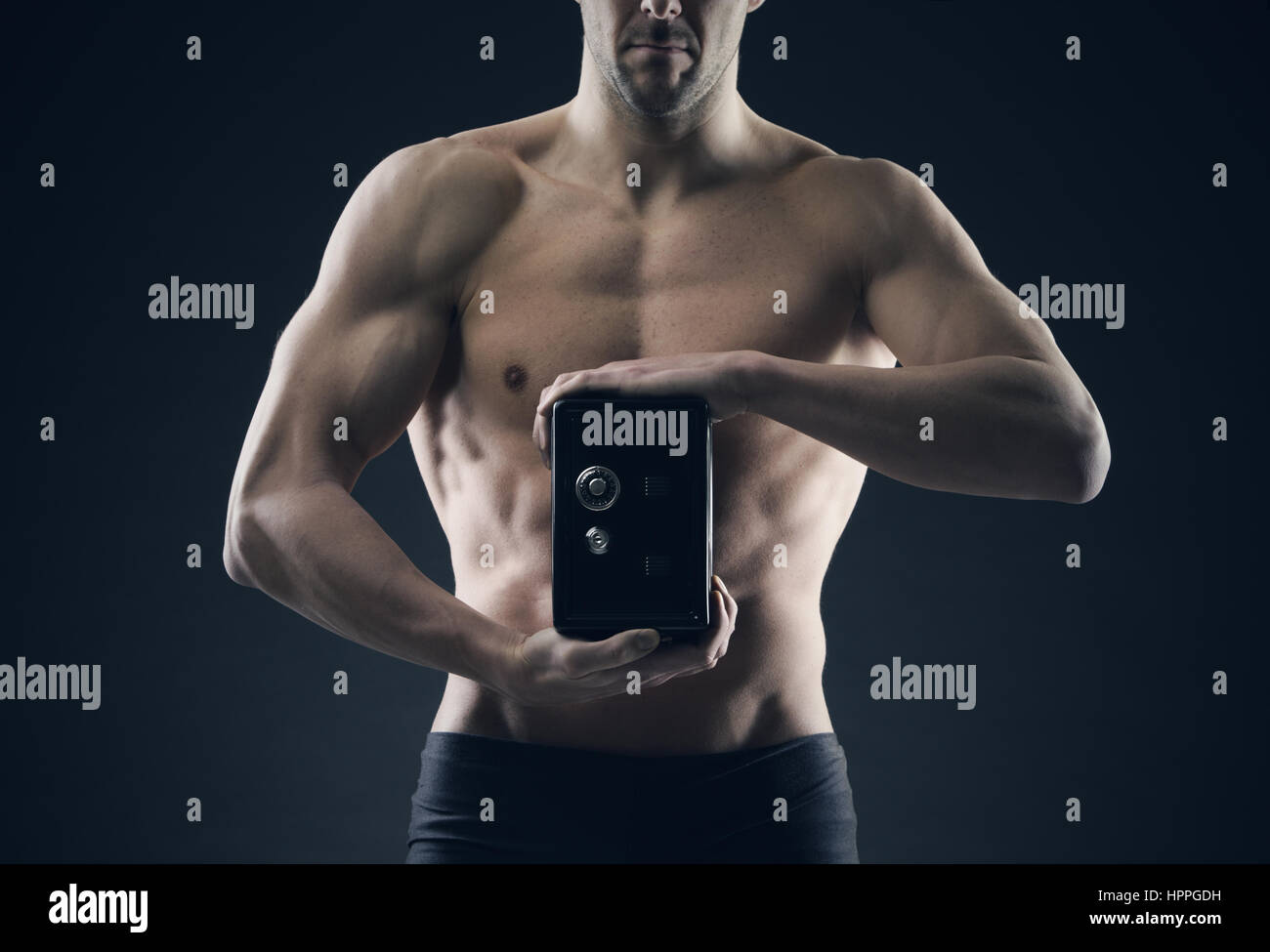 Muscular man protects savings in the safe Stock Photo - Alamy