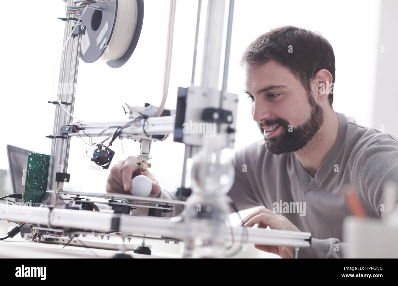 Young designer engineer using a 3D printer in the laboratory and ...