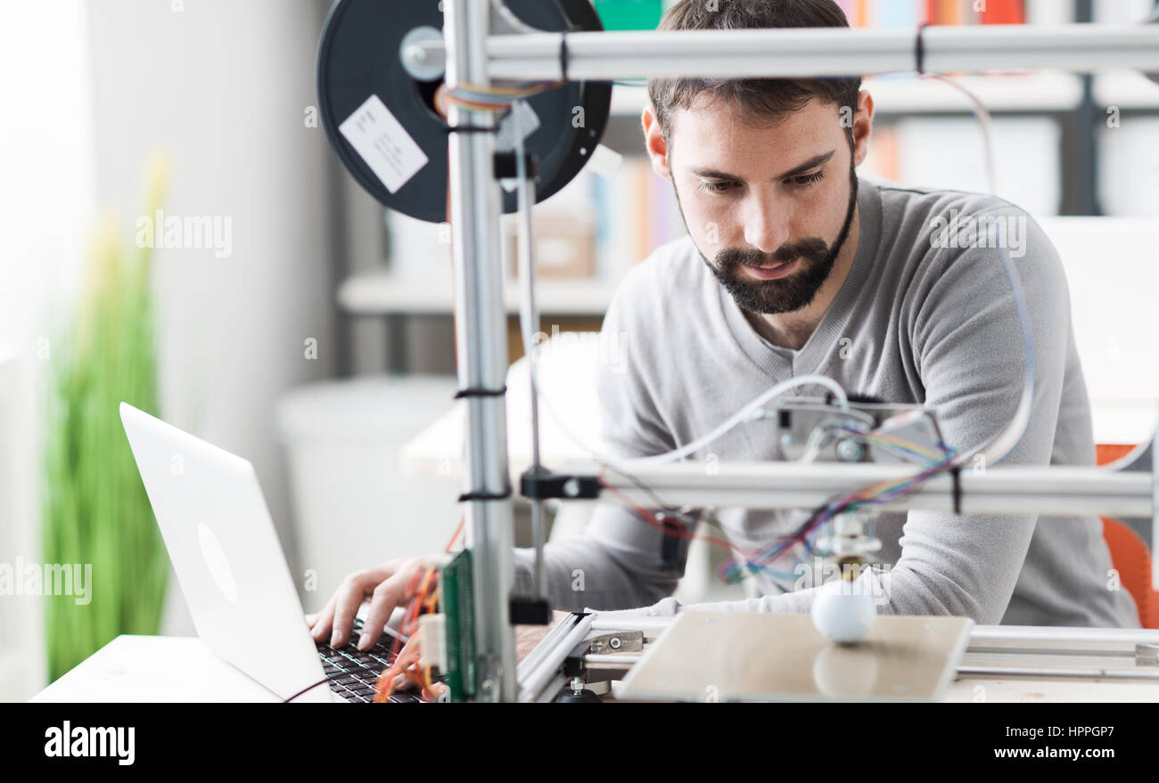 Young designer engineer using a 3D printer in the laboratory and ...
