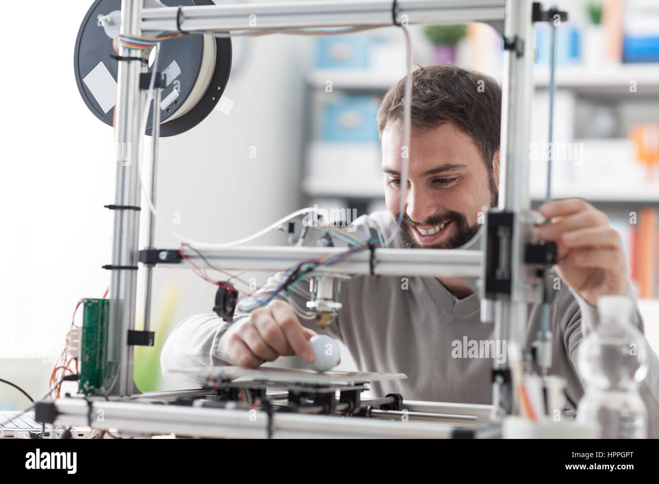 Young designer engineer using a 3D printer in the laboratory and ...
