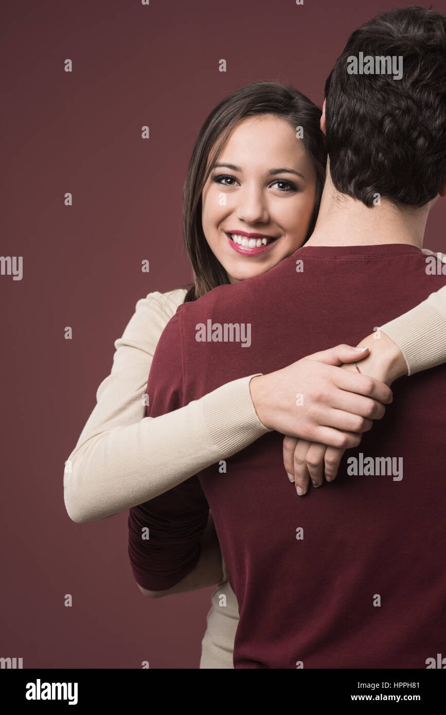 Happy young woman hugging her boyfriend on red background Stock Photo - Alamy