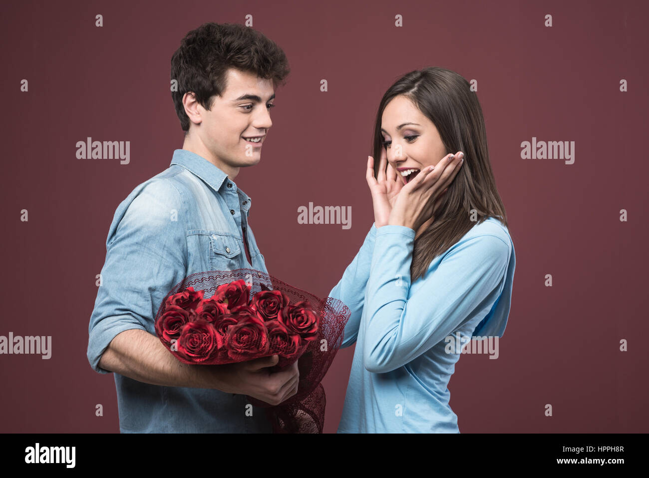 Smiling young woman receiving red roses as love gift from her boyfriend ...