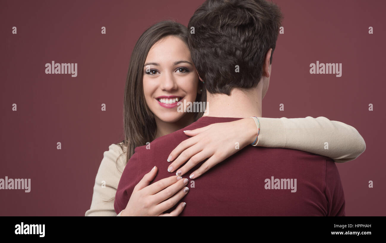 Happy young woman hugging her boyfriend on red background Stock Photo - Alamy
