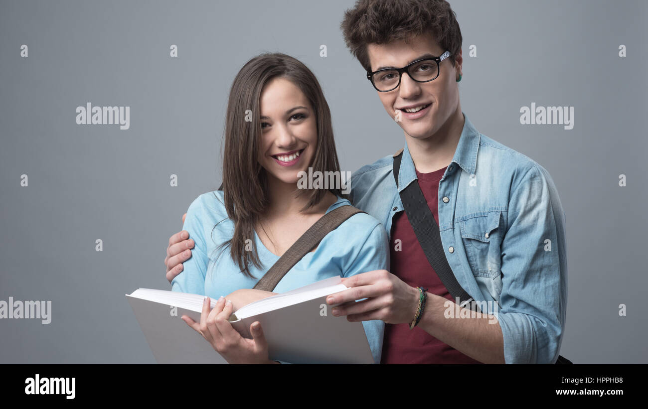 Happy students studying together on an open textbook and smiling Stock ...