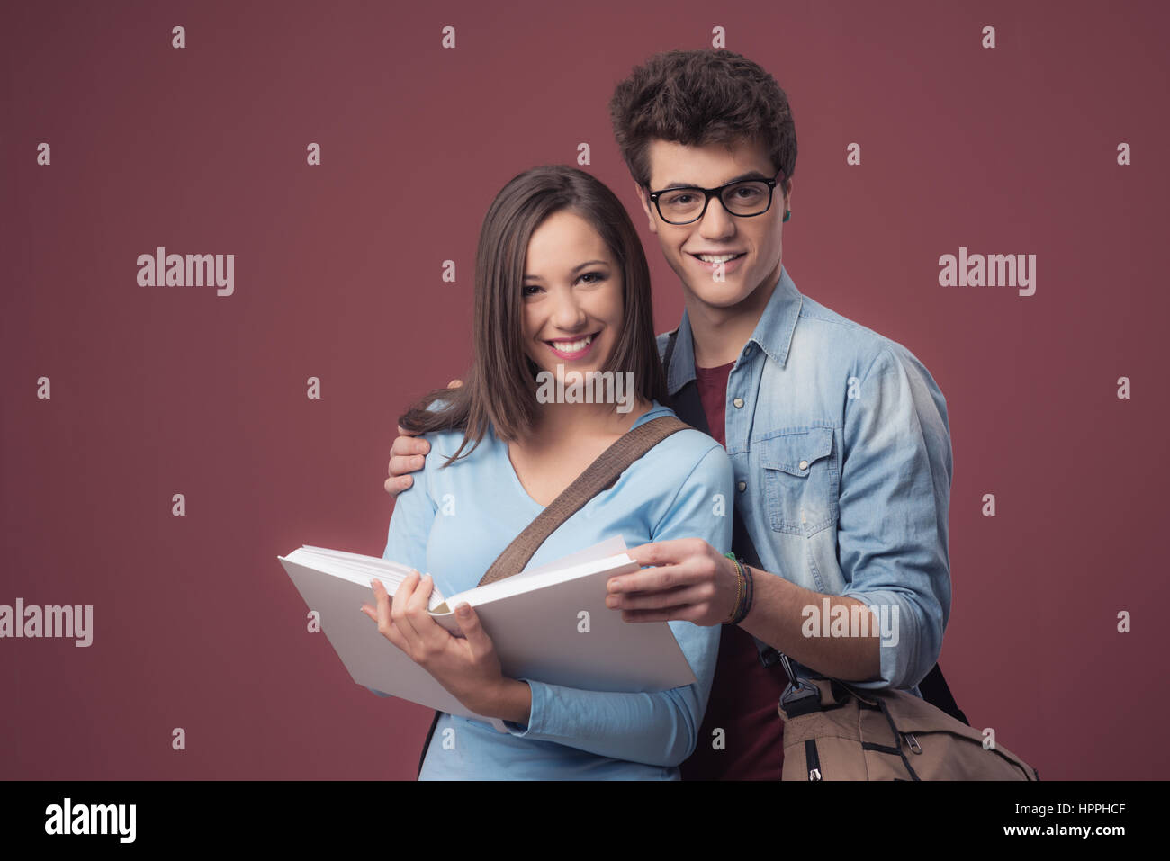 Happy students studying together on an open textbook and smiling Stock ...