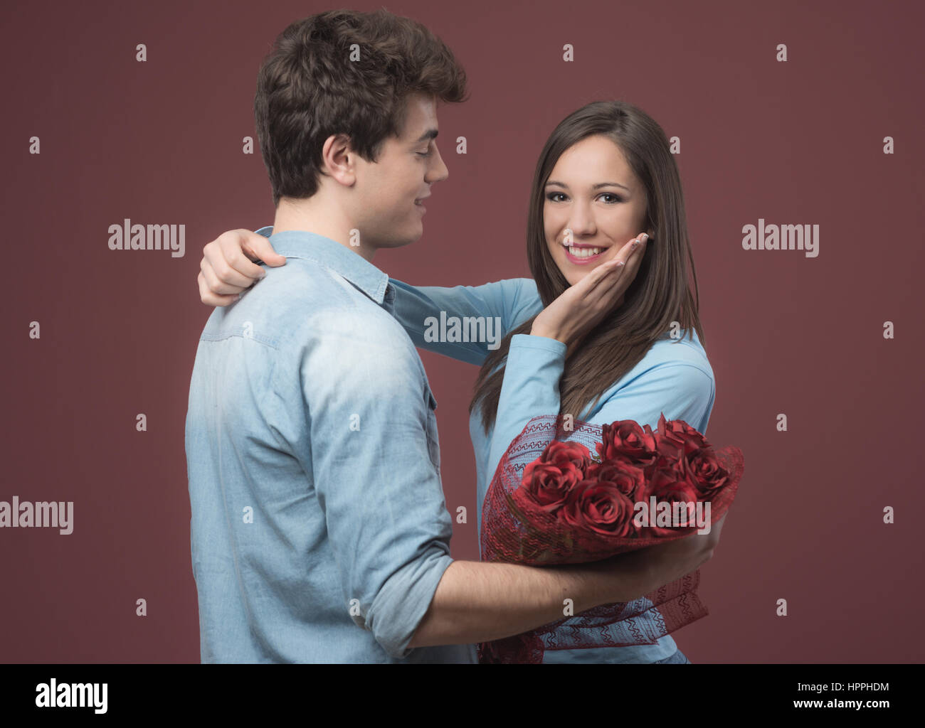 Smiling young woman receiving red roses as love gift from her boyfriend ...