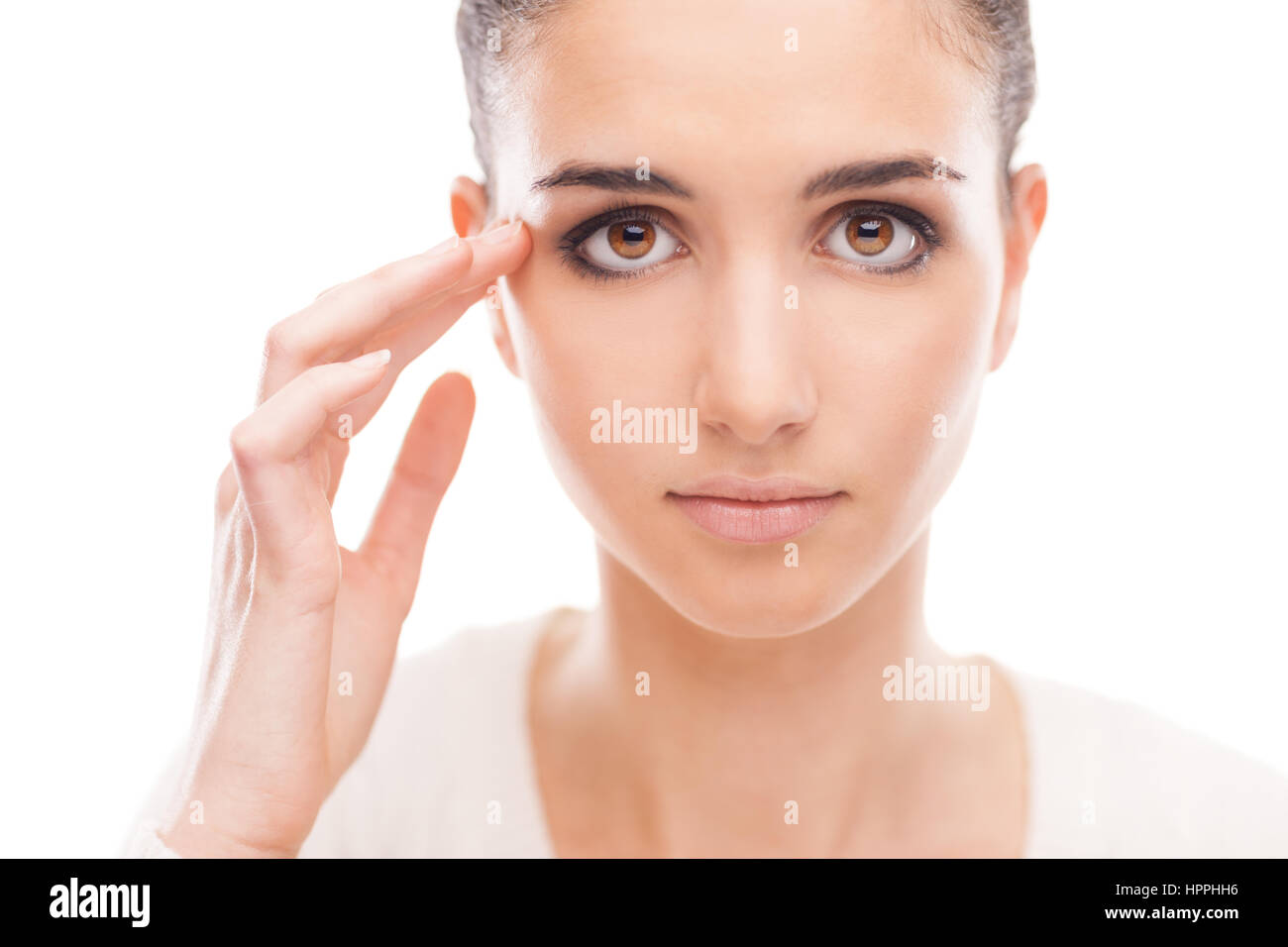 Beautiful young woman checking her face skin and looking at camera ...