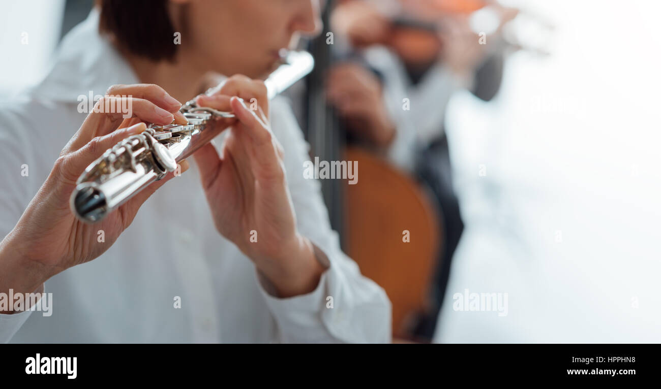 Professional female flute player performing with classical music ...