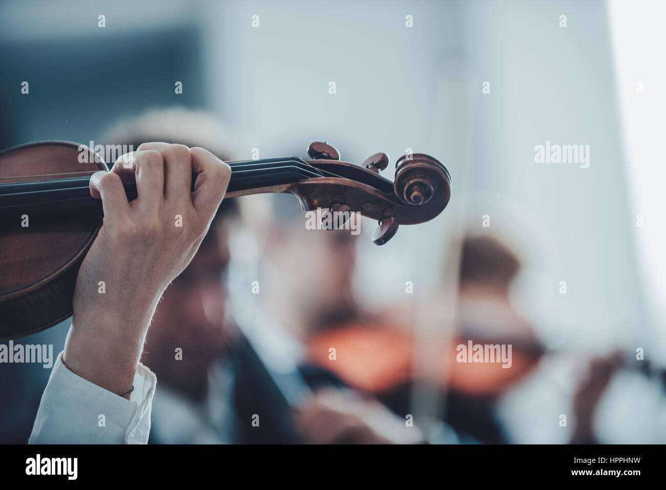 Female violinist performing and orchestra on background, selective focus, music and arts concept ...