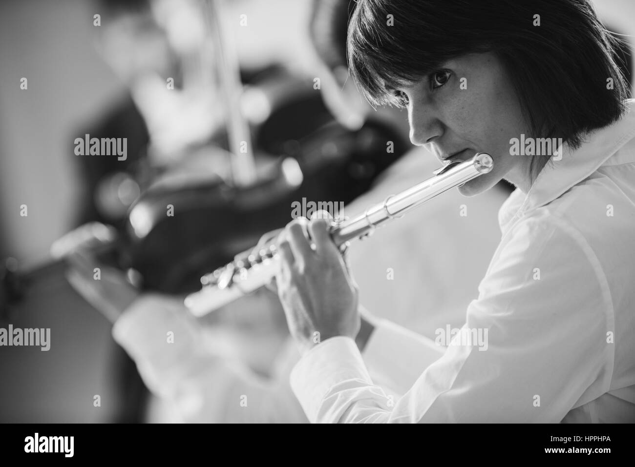 Professional female flustist playing her instrument on stage with ...