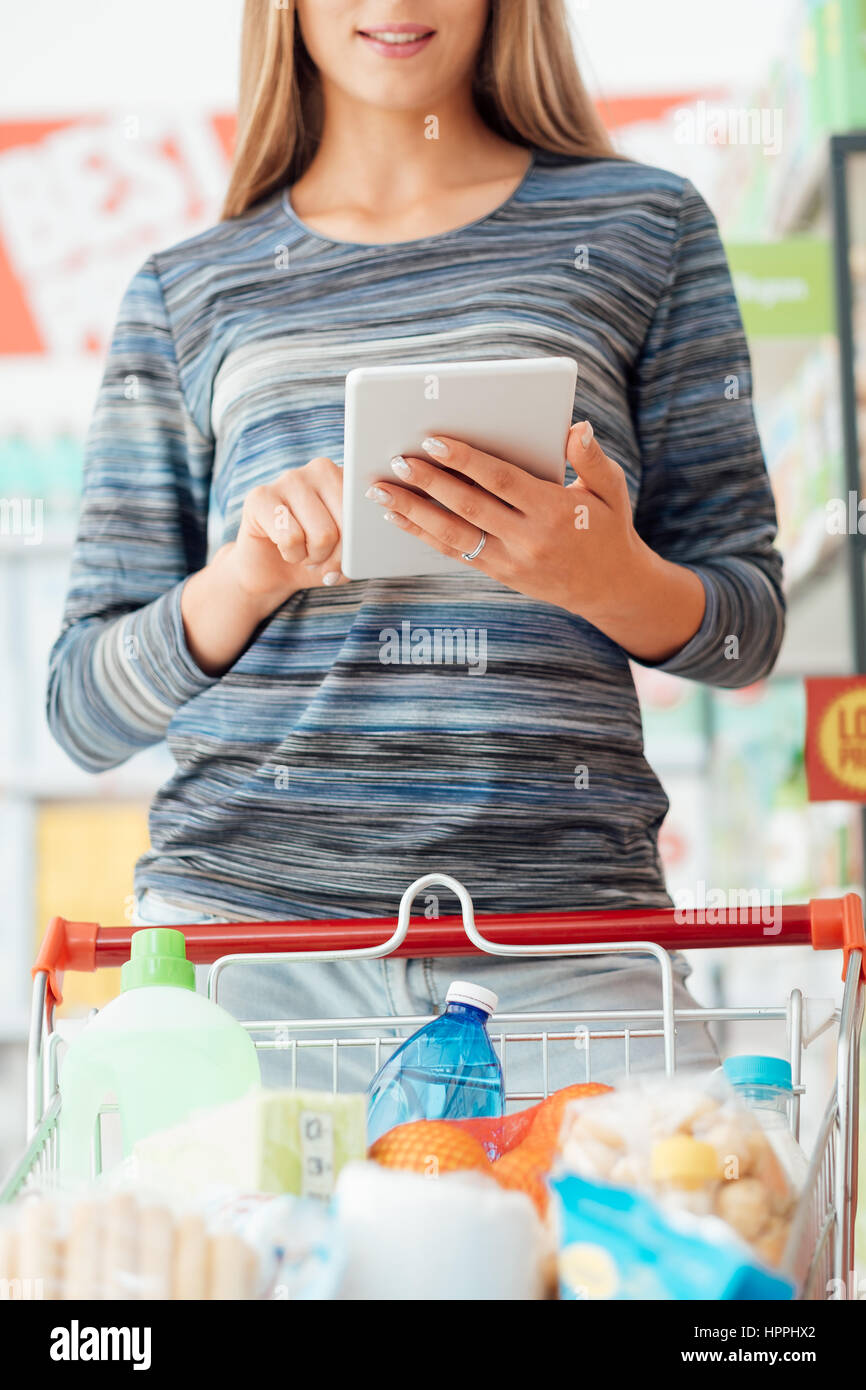 Woman doing grocery shopping and using apps on her digital tablet ...