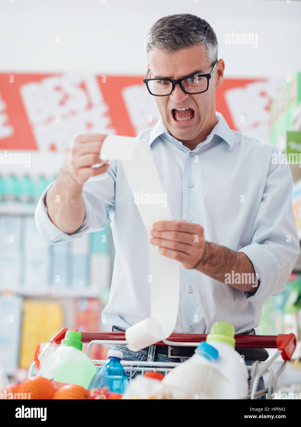 Shocked man doing grocery shopping at the supermarket and checking a ...
