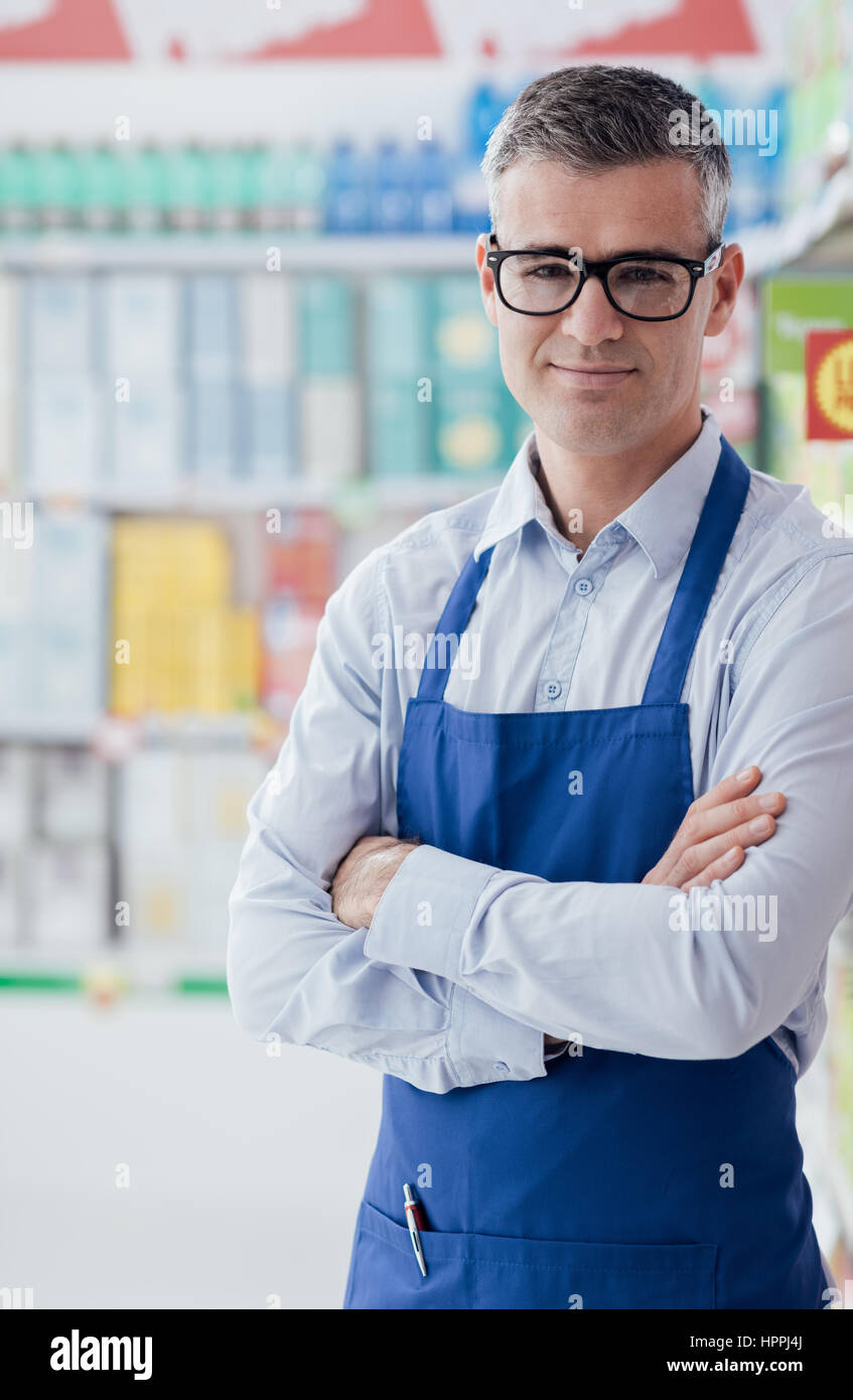 Confident smiling supermarket clerk posing at the shopping mall, retail ...