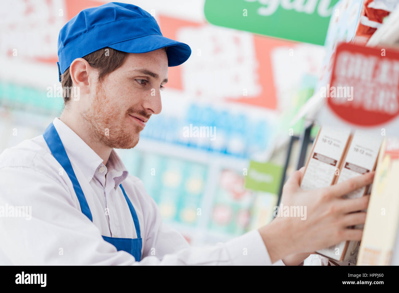 Professional supermarket clerk working in the store aisle, he is ...