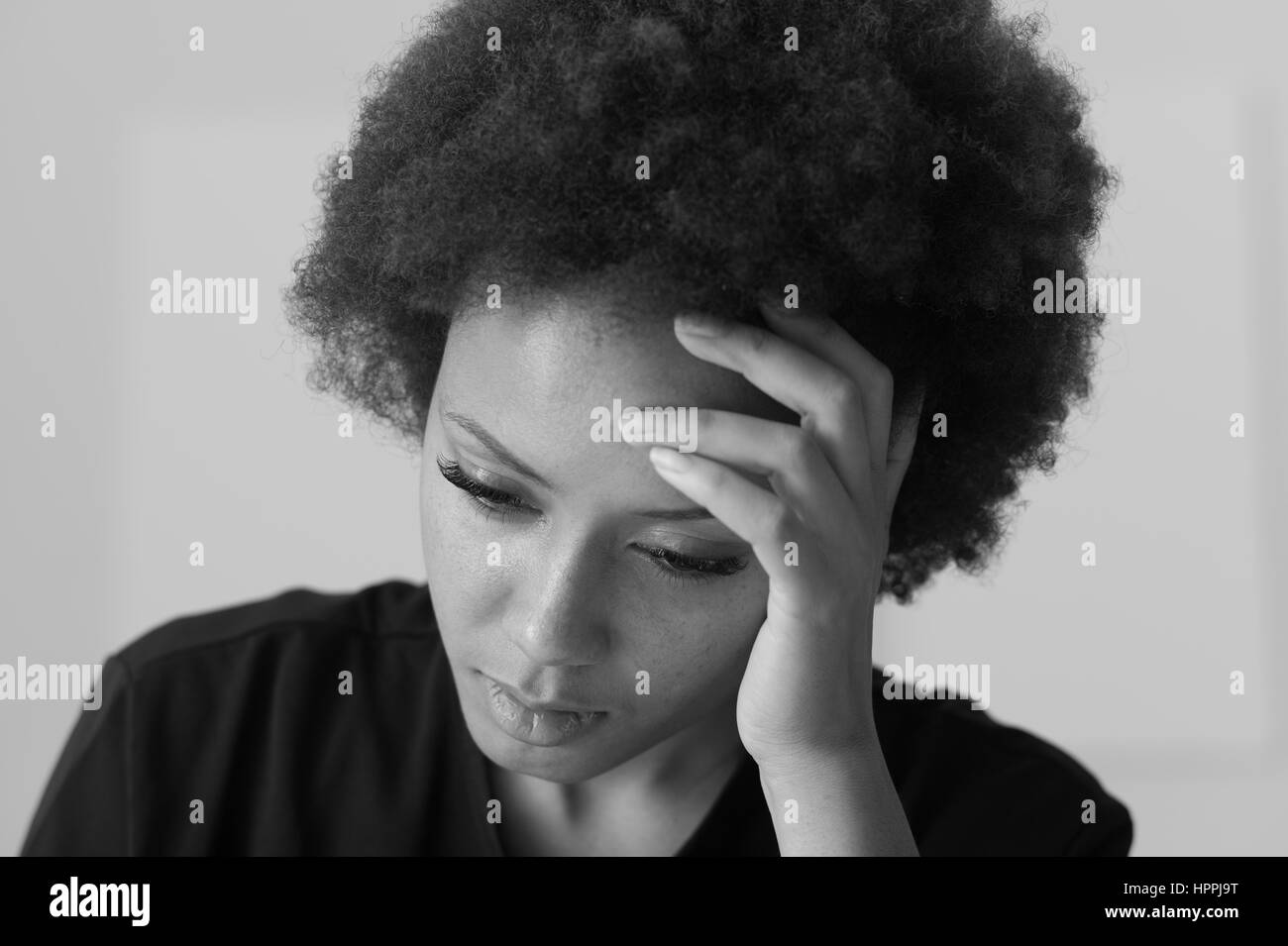 Sad african american woman touching her forehead and looking down, she ...