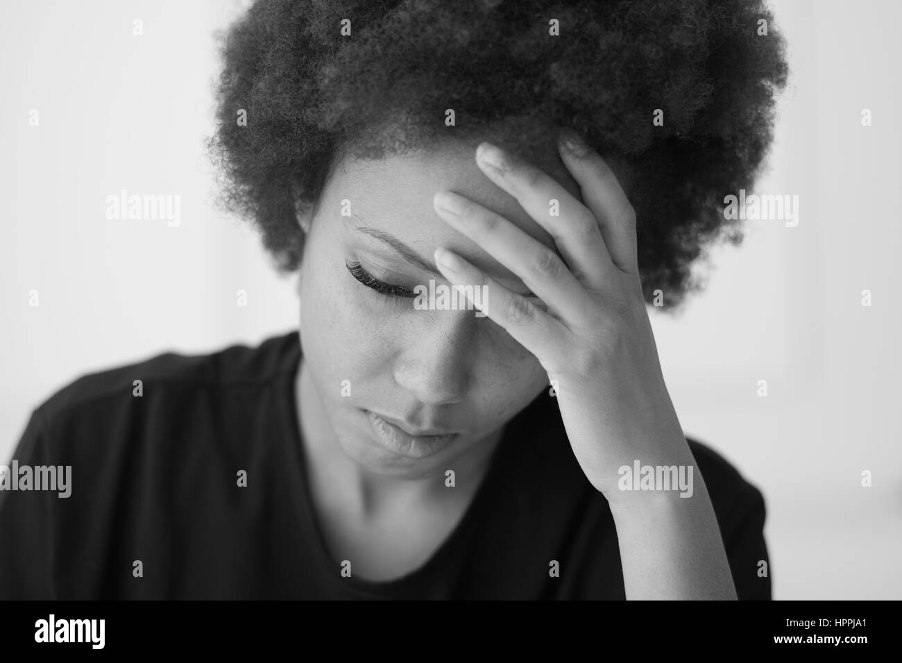 Sad african american woman touching her forehead and looking down, she ...