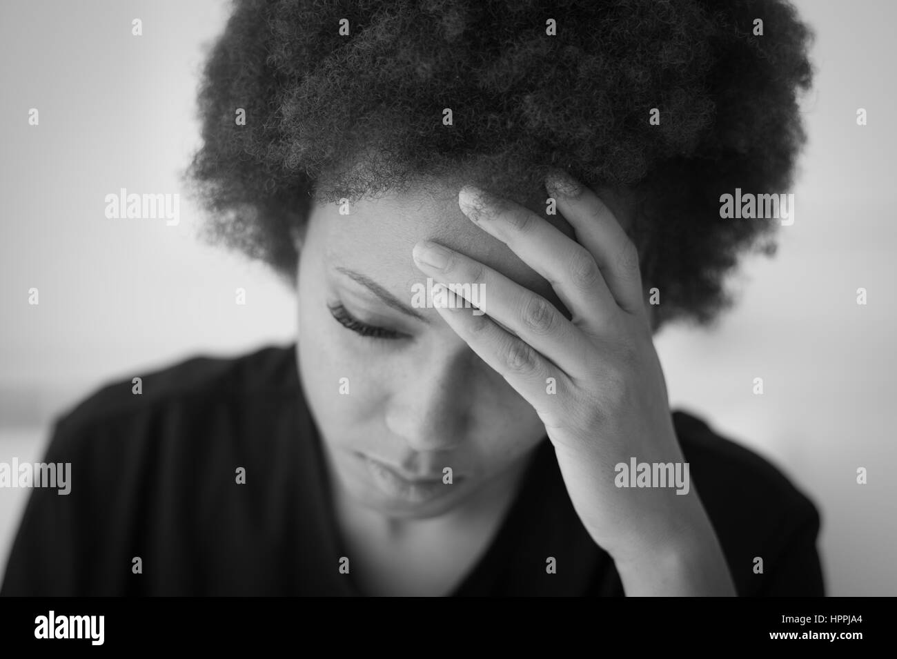 Sad african american woman touching her forehead and looking down, she ...