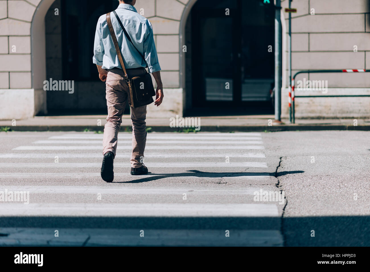 Man walking in the city and crossing the street, back view Stock Photo ...