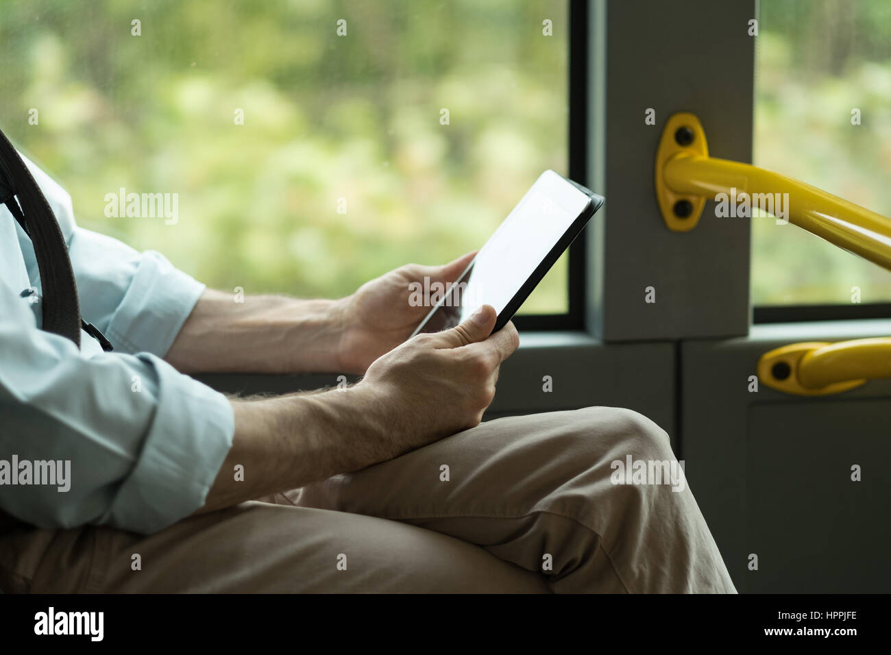 Man commuting to work by bus and working with a digital touch screen ...