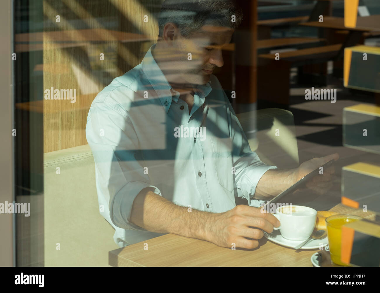 Man having breakfast at the cafe next to a window with reflections ...