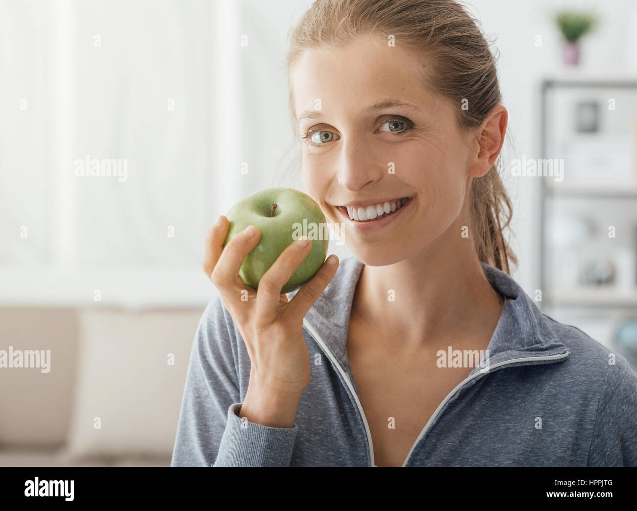 Confident smiling woman eating an apple after working out, fitness and ...