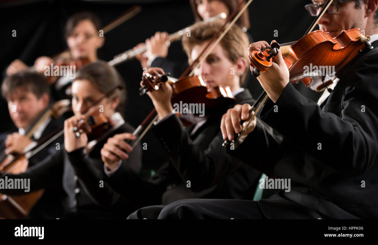 Symphony orchestra first violin section performing on dark background ...