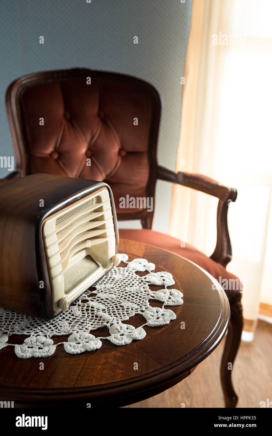 Vintage radio on round table with doily and living room on background ...