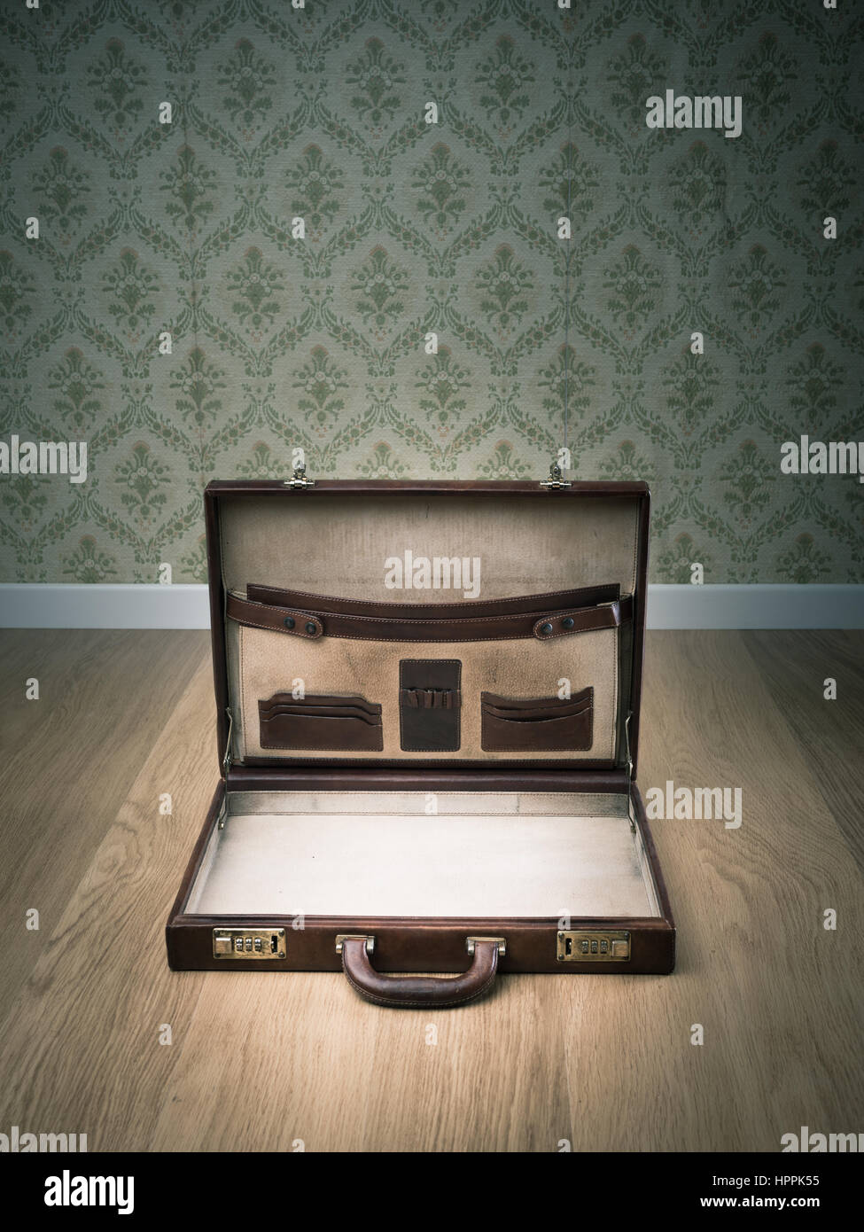 Open vintage leather briefcase on hardwood floor, retro wallpaper on ...