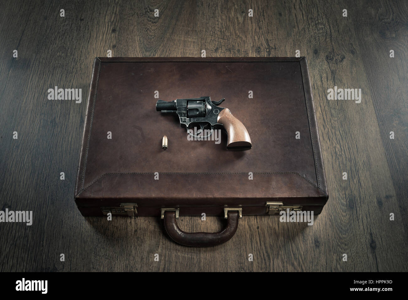 Vintage revolver gun on leather briefcase with bullet on wooden table ...