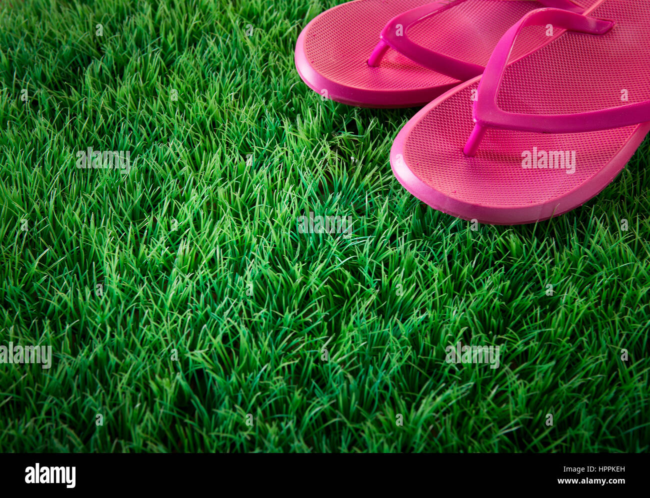 Pink flip flops on green lush artificial grass, summer and vacations ...