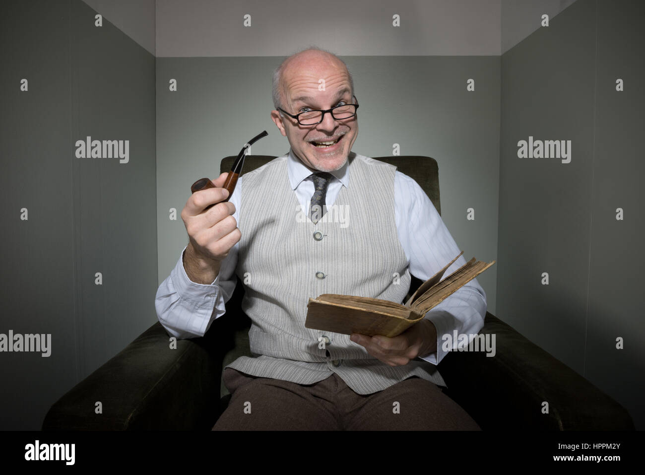 Senior cheerful man reading in armchair and smoking pipe Stock Photo ...