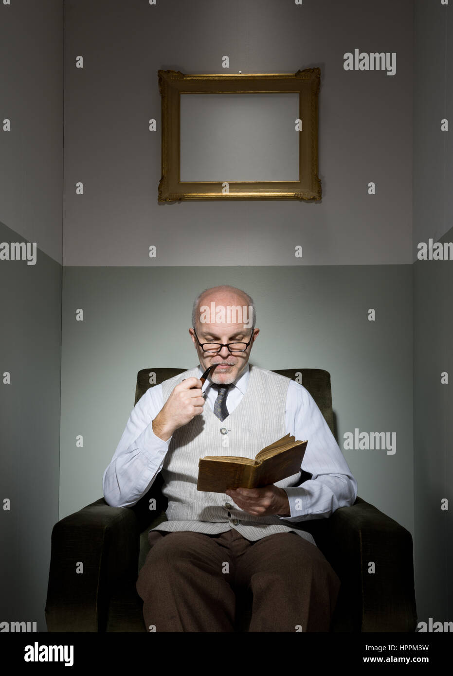 Senior handsome man reading in armchair and smoking pipe Stock Photo ...