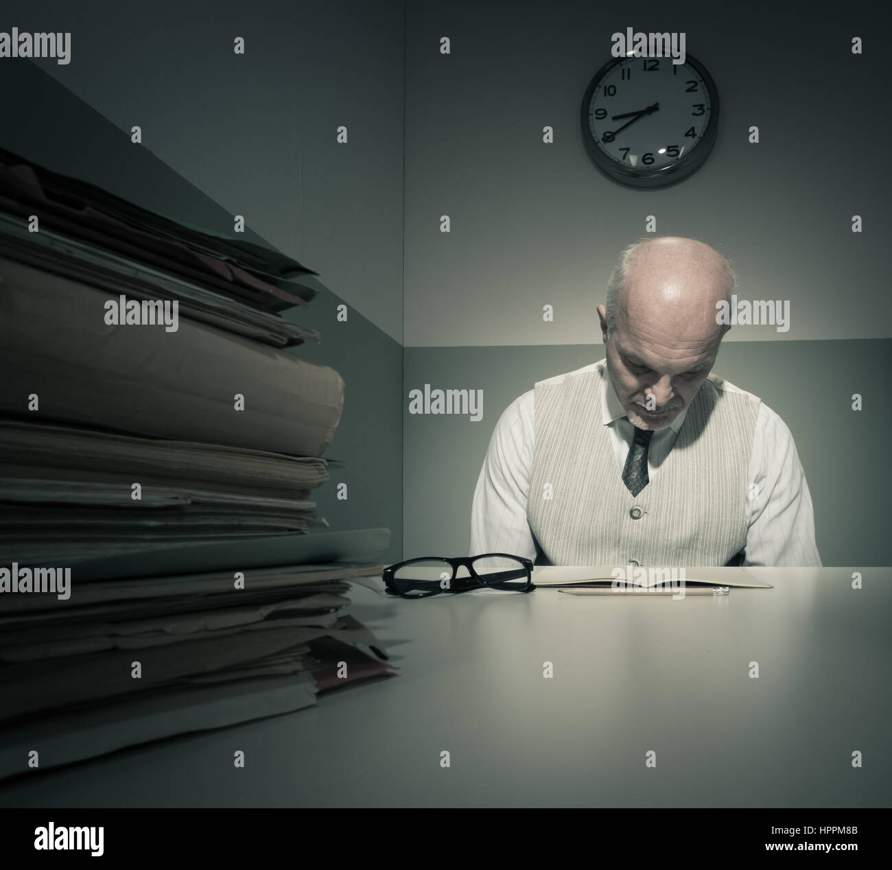 Tired sad clerk reading documents in his small office Stock Photo - Alamy