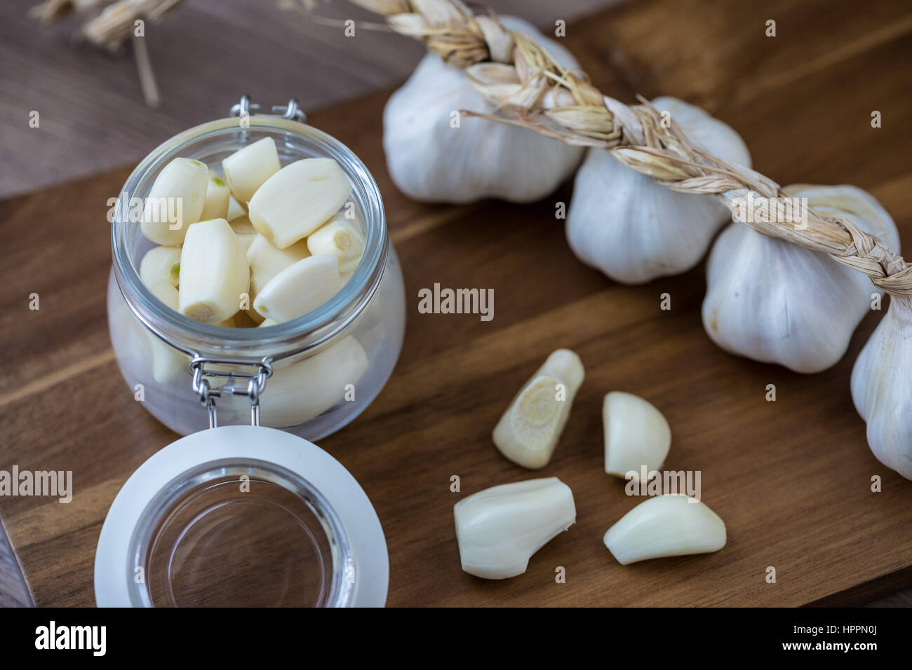 Peeled garlic in a glass container with garlic clove and bulb and a ...