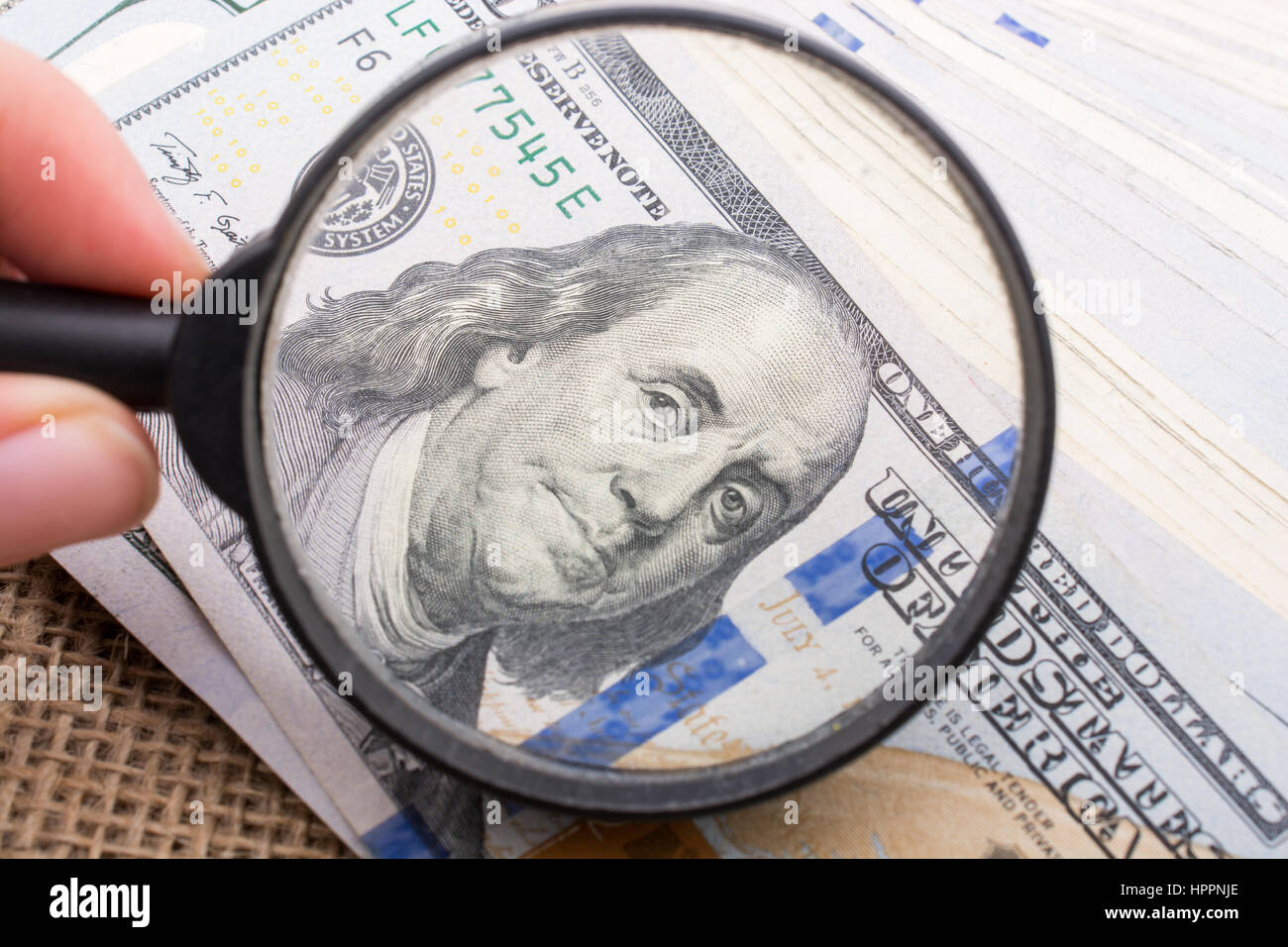 Magnifying glass is held over the banknote bundle of US dollar Stock ...