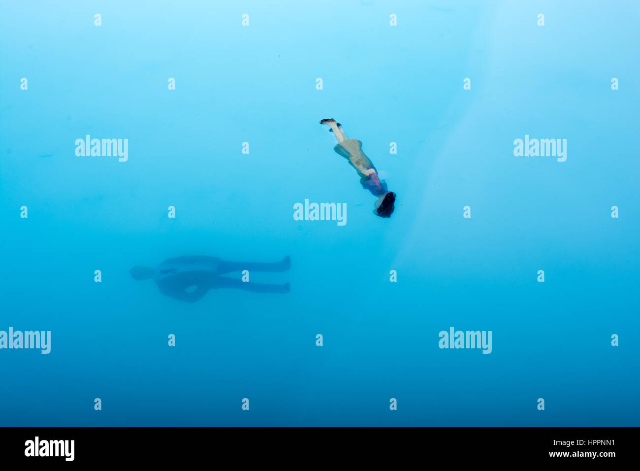Little floating figurines in blue water Stock Photo - Alamy