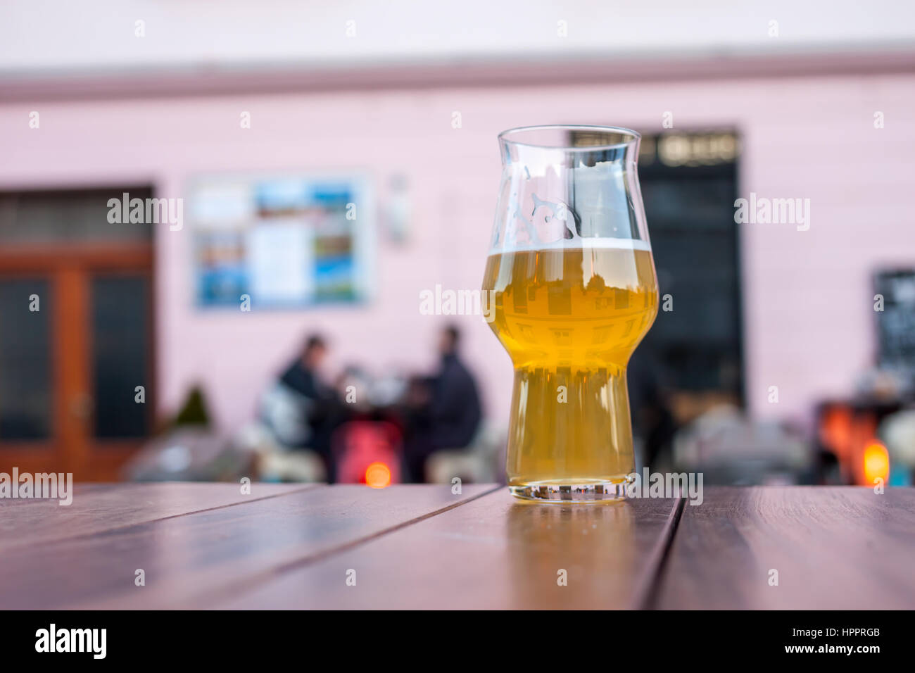 glass of beer on table edge outside bar background Stock Photo - Alamy