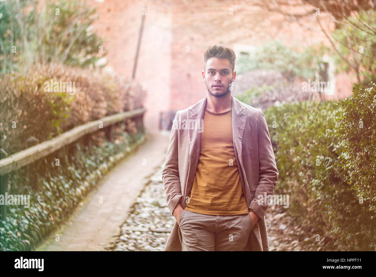Handsome young man walking along rural road, looking confident and ...