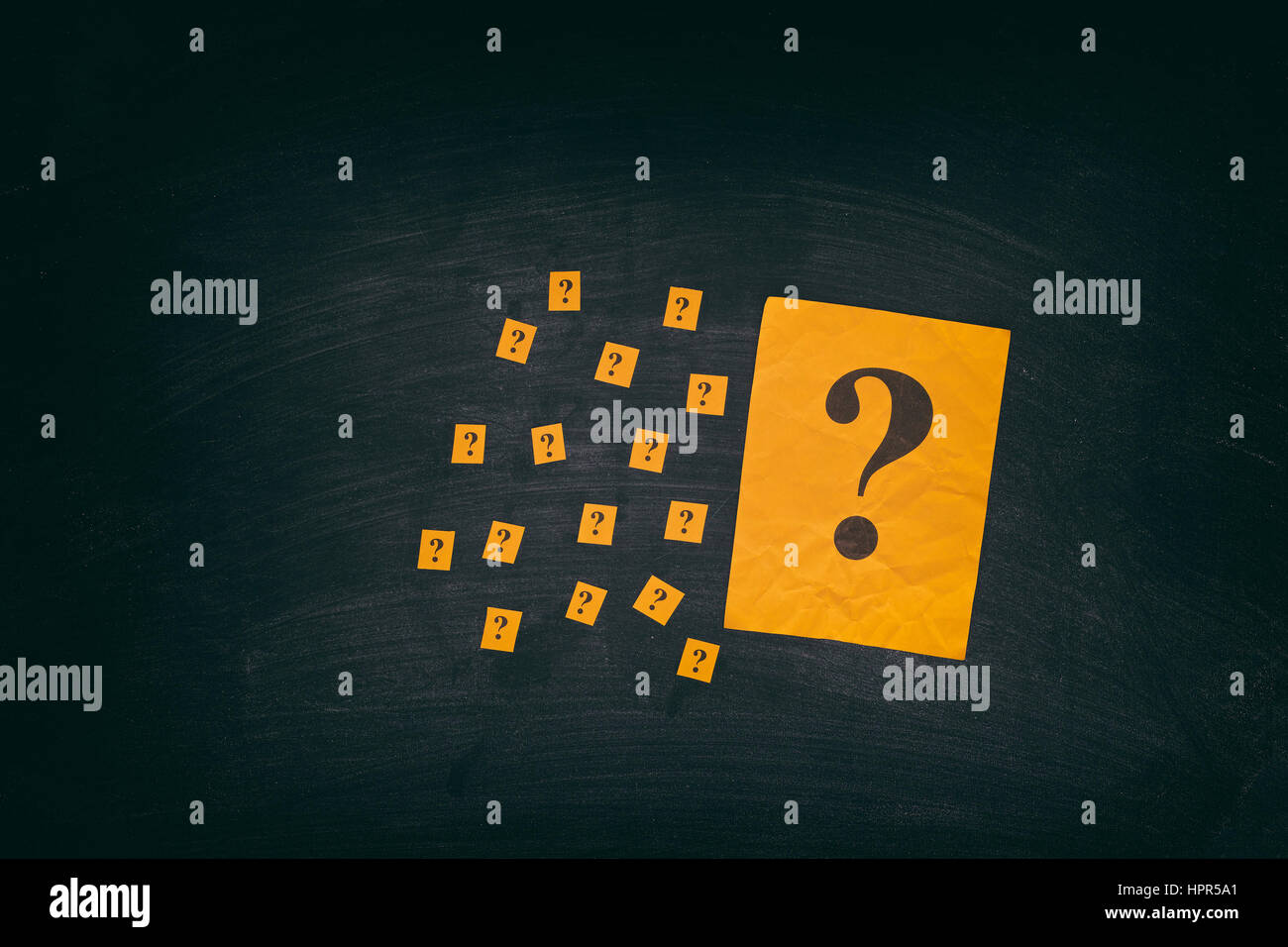 Yellow paper notes with question marks on black board. Close up Stock ...