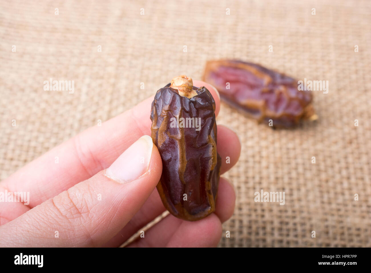 hand holding a date on a linen canvas background Stock Photo - Alamy